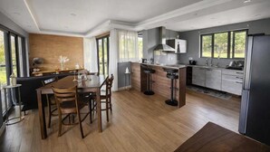 Uma cozinha moderna com área de jantar, grandes janelas e fogão embutido.