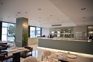Um restaurante moderno com área de bar, mesas e vista para o exterior.