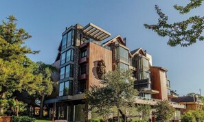 Um edifício de vários andares com design arquitetônico moderno, com grandes janelas e uma combinação de materiais.