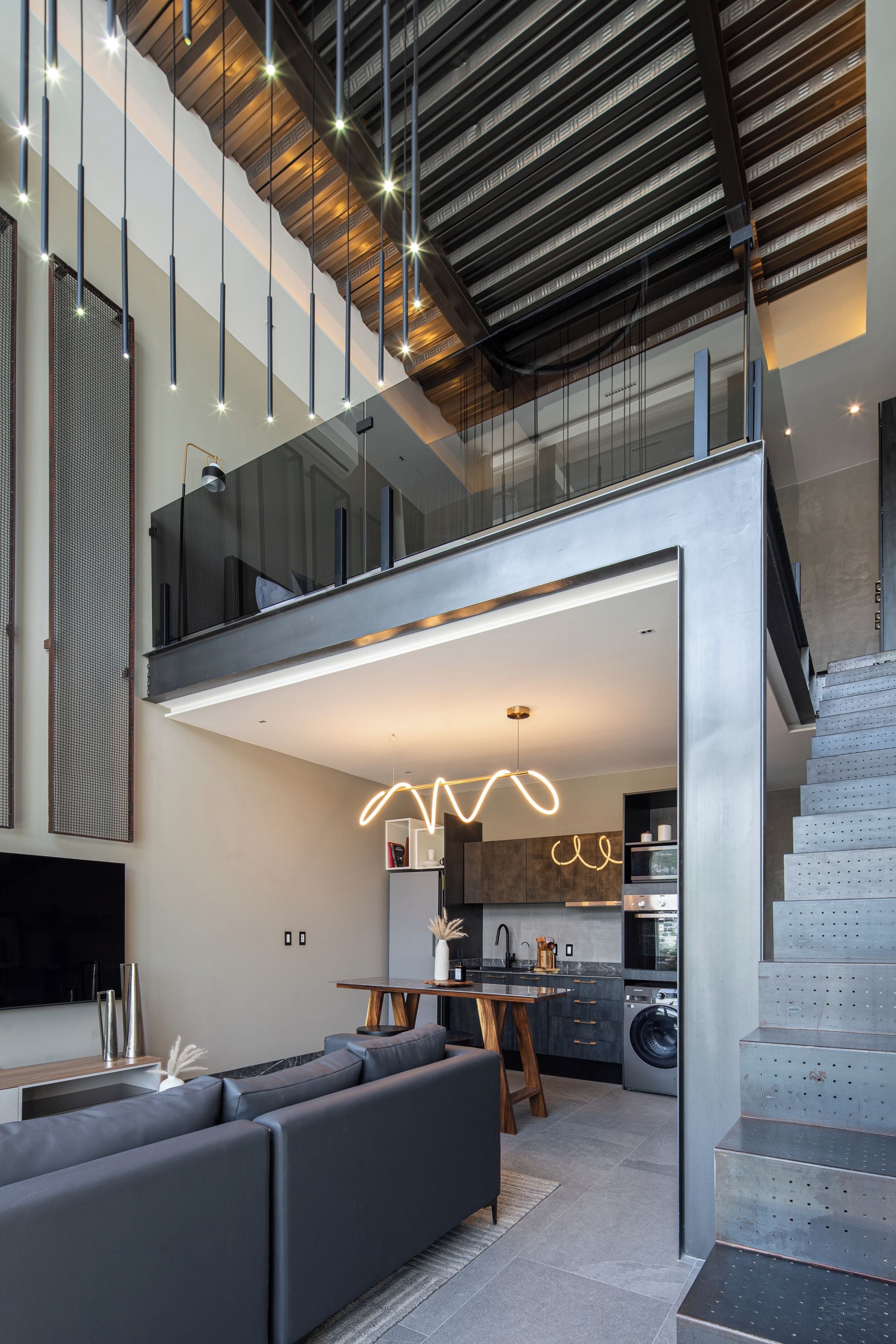 Um interior moderno com área de estar, cozinha e escada.