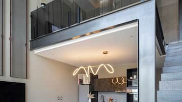 Um interior moderno com área de estar, cozinha e escada.