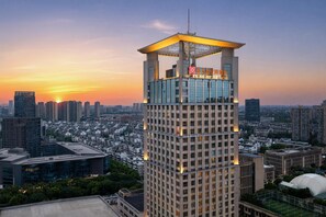 Um hotel imponente com uma arquitetura marcante no topo, inserido em uma paisagem urbana movimentada.