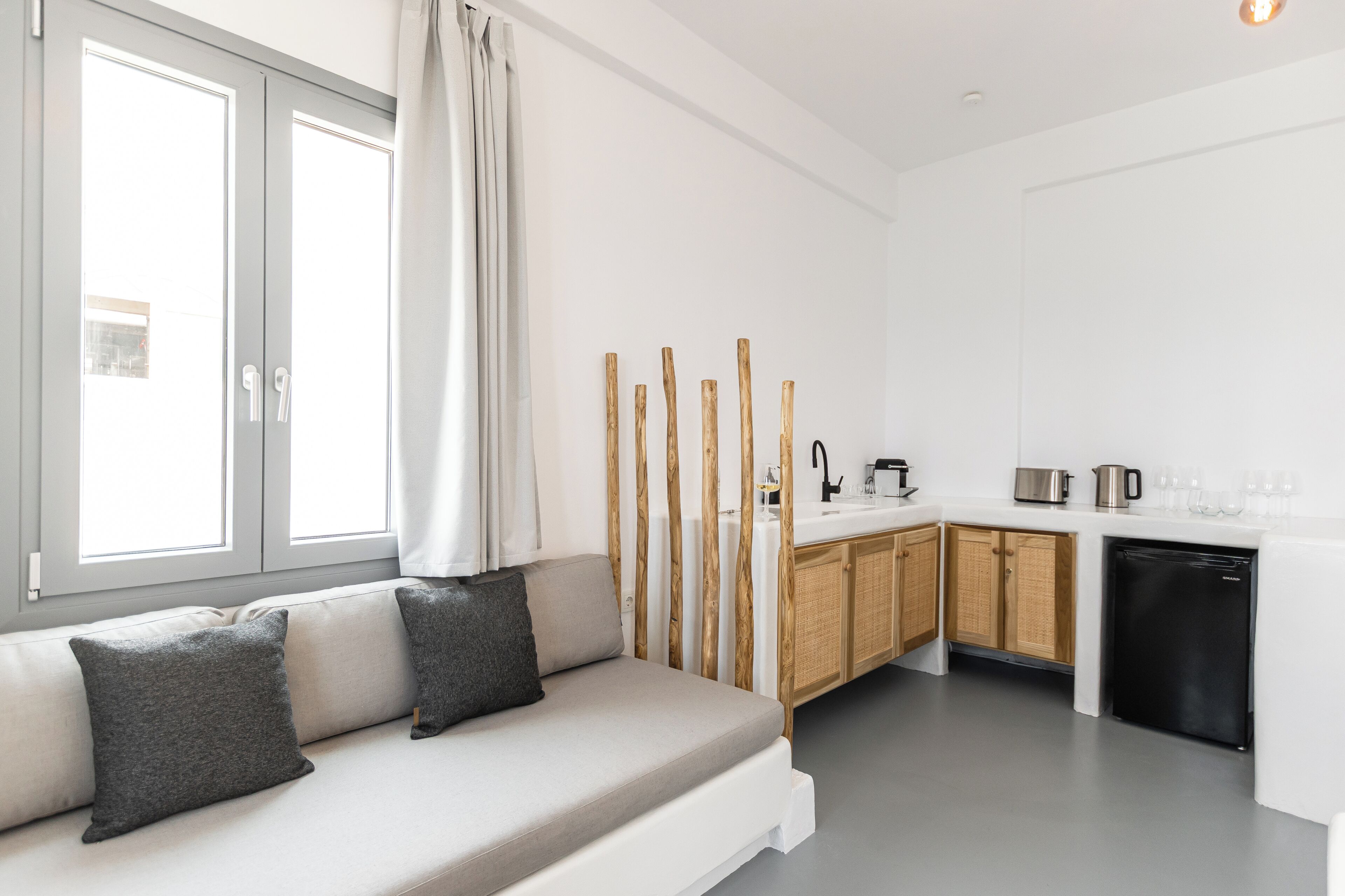 Uma sala de estar moderna com um sofá, uma área de jantar com cozinha e uma grande janela com cortinas.