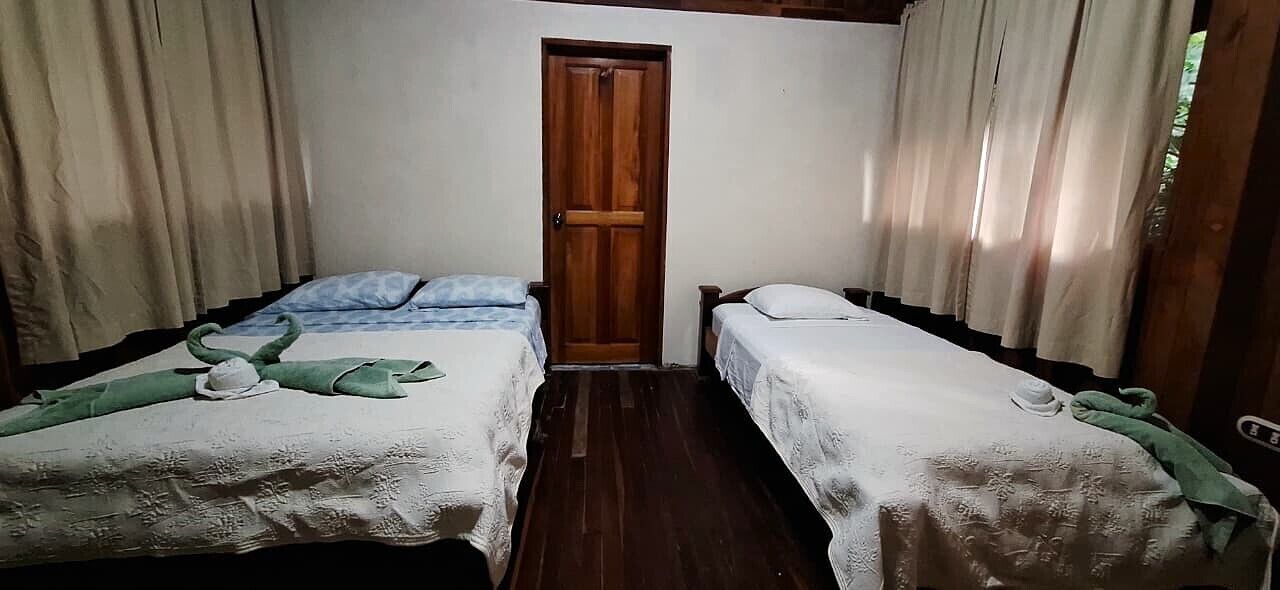 Quarto com duas camas, porta de madeira e cortinas.