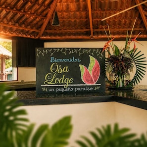Placa de boas-vindas na Osa Lodge com tema tropical, incluindo uma ilustração de melancia e uma planta.