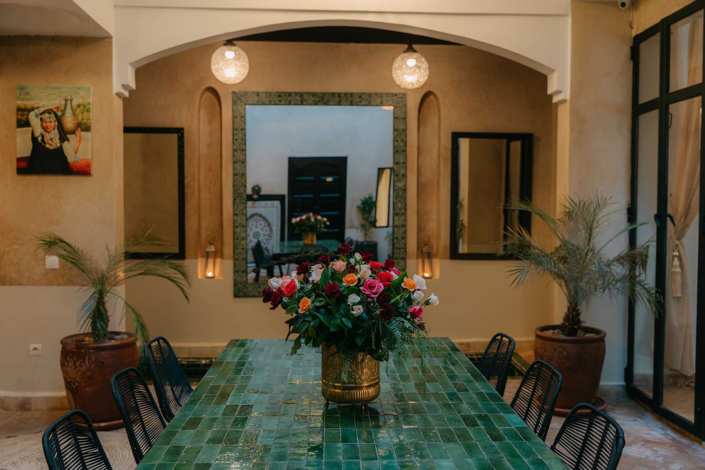 Uma sala de jantar com uma mesa de azulejos verdes, cadeiras e um arranjo floral.
