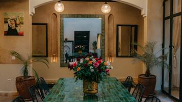 Uma sala de jantar com uma mesa de azulejos verdes, cadeiras e um arranjo floral.