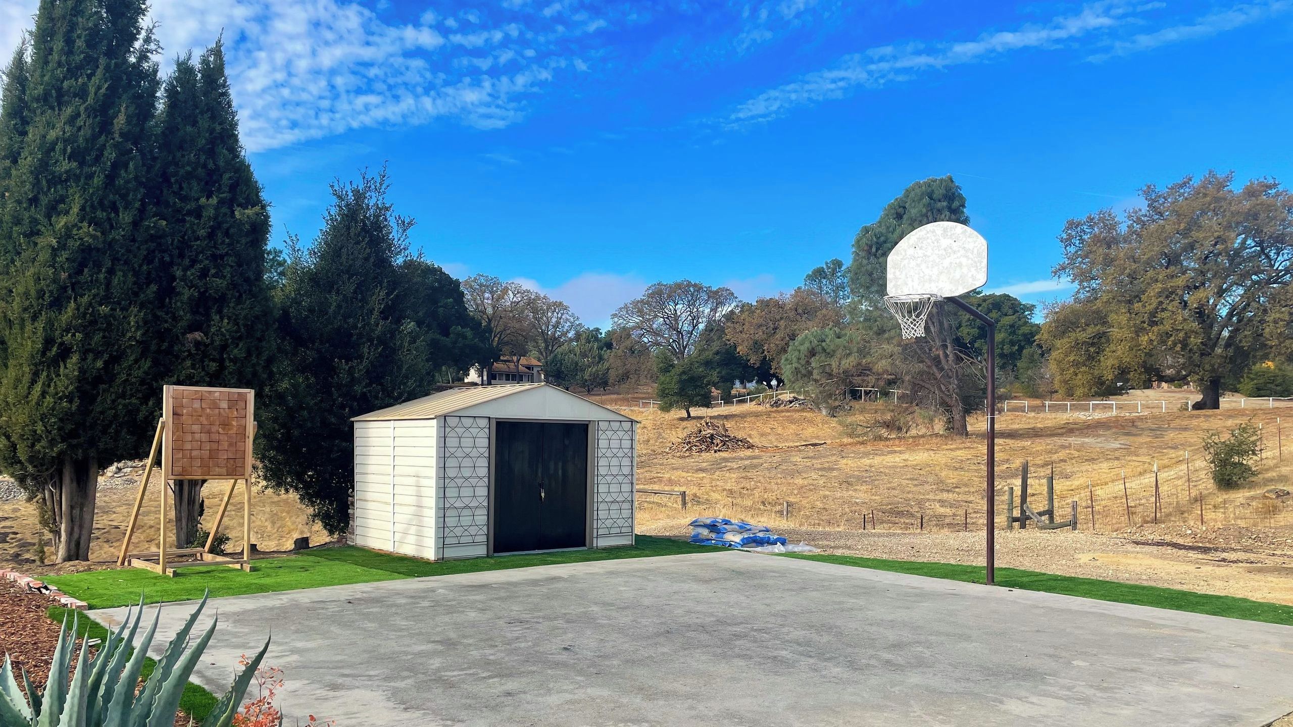 Um pequeno edifício térreo com uma porta de garagem, cercado por gramado e árvores.