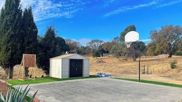 Um pequeno edifício térreo com uma porta de garagem, cercado por gramado e árvores.