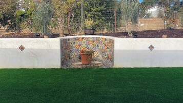 Paredes com um padrão decorativo de azulejos, um vaso de planta e uma pequena escultura de pedra.