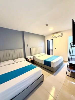 Quarto de hotel com duas camas, mesa de cabeceira e unidade de ar condicionado.
