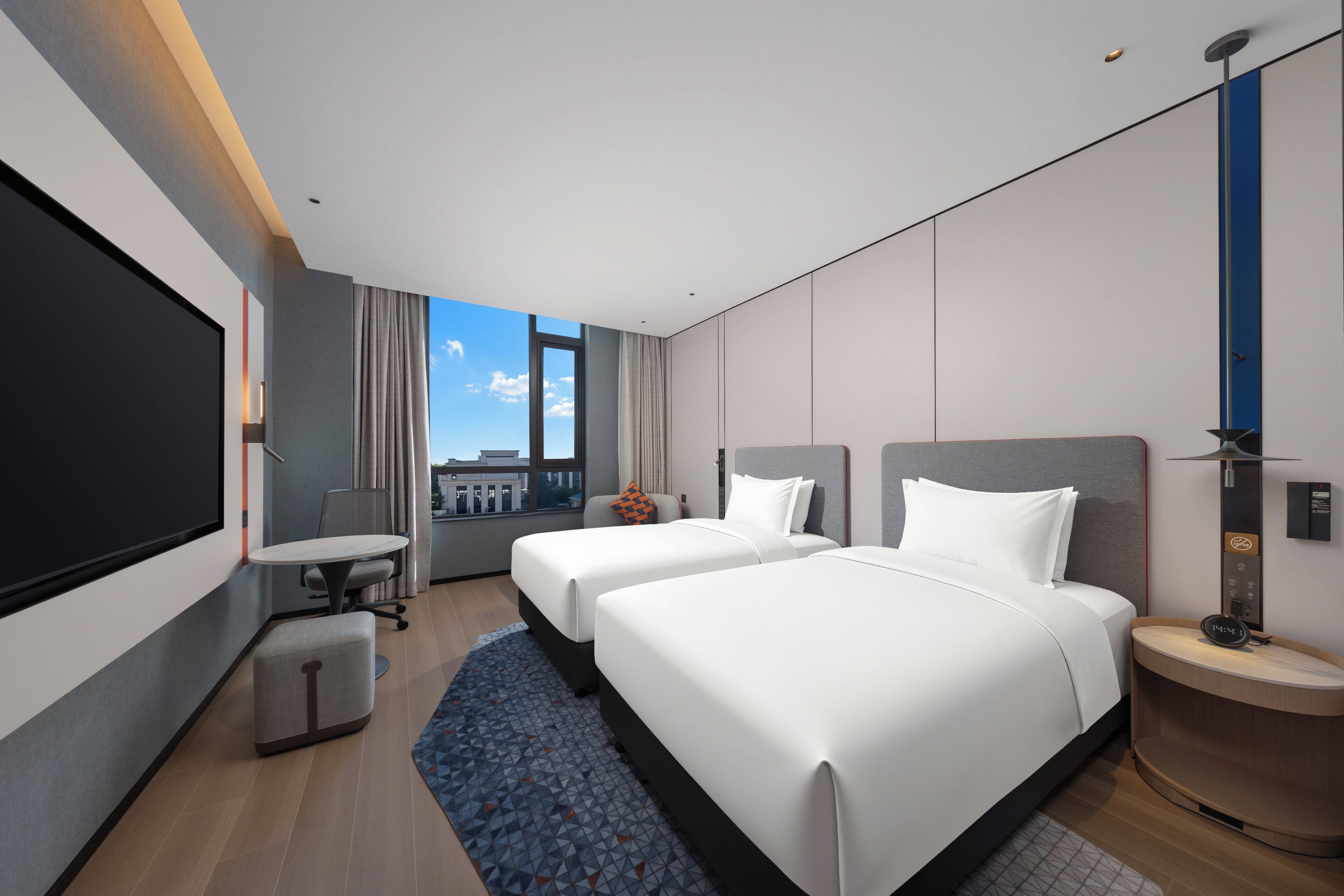 Quarto de hotel com duas camas, uma escrivaninha, uma cadeira, televisão e vista para a cidade.