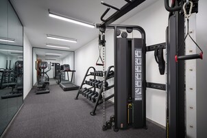 Academia com equipamentos de ginástica, esteiras e um espelho.