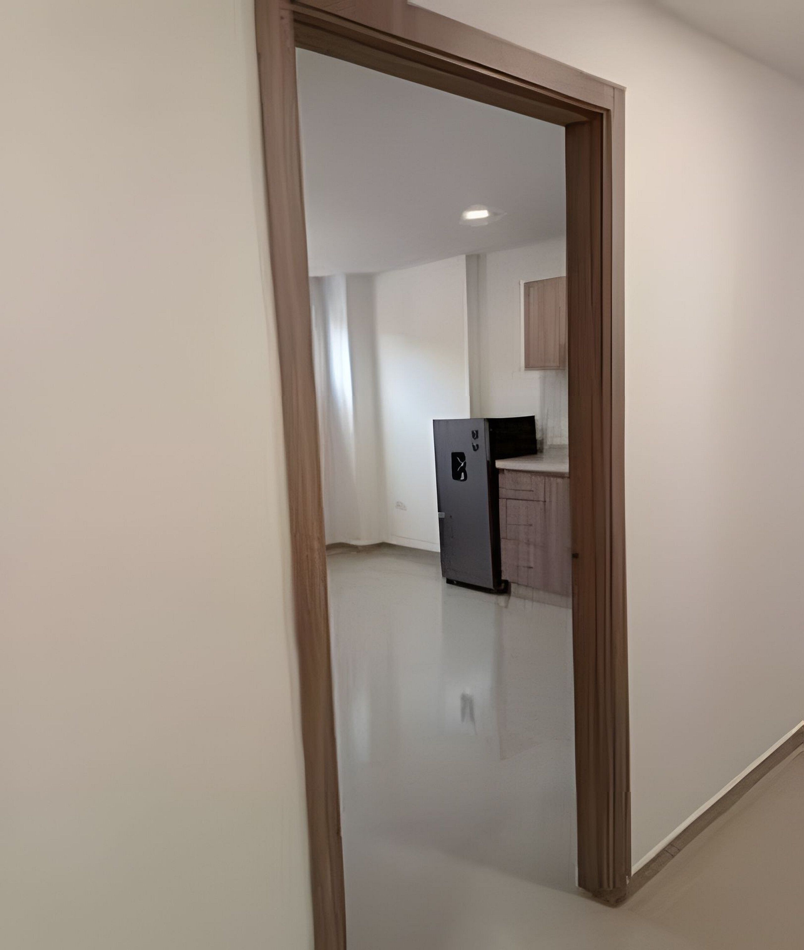 Corredor que leva a uma cozinha com frigorífico e armários.