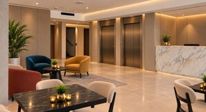 Um lobby moderno com balcão de atendimento, elevadores e área de estar com mesas e cadeiras.
