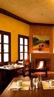 Uma sala de jantar com lareira, móveis de madeira e um quadro na parede.