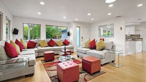 Uma sala de estar moderna com dois sofás, uma mesa de centro de vidro e pufes vermelhos.