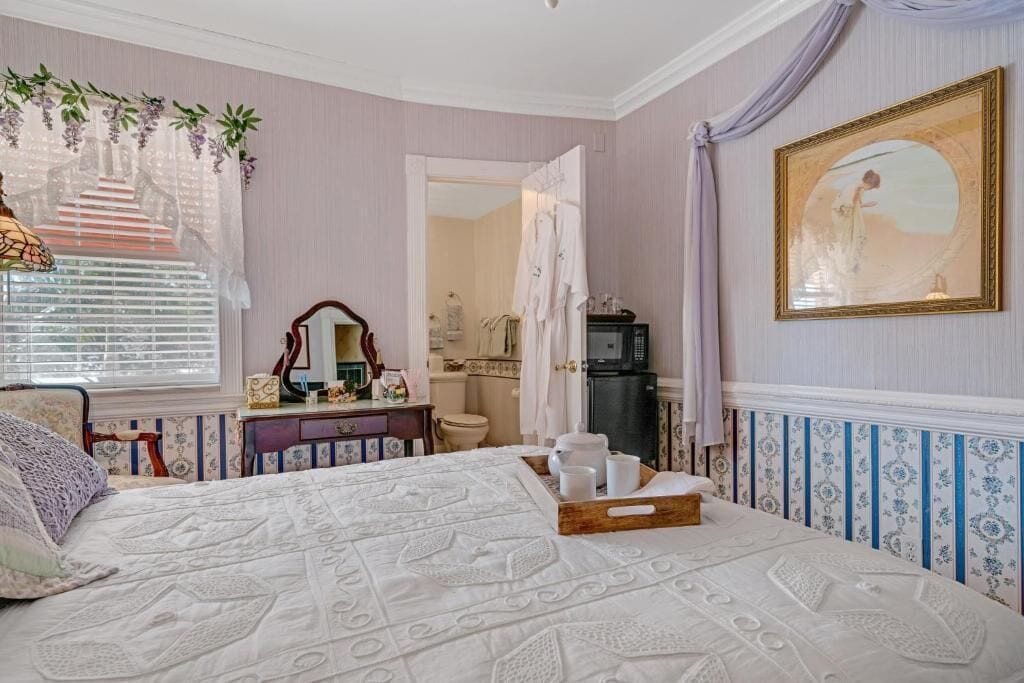 Quarto com cama grande, cômoda, espelho e um quadro na parede.