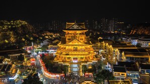 Um edifício tradicional com vários andares, letreiros iluminados e uma rua movimentada em primeiro plano.