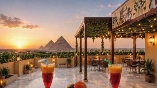 Terraço no terraço com vista para pirâmides, duas bebidas e um prato de frutas.