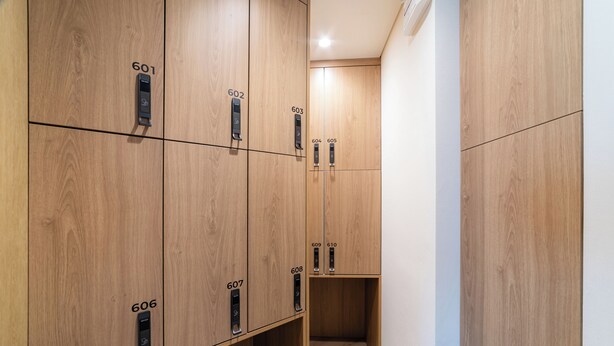 Um elevador moderno com painéis de madeira e portas numeradas, dando acesso a um corredor.