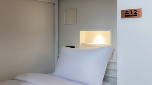 Quarto de hotel com cama, mesa de cabeceira, abajur e placa na parede com o número 412.