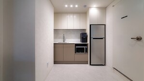 Uma cozinha moderna com micro-ondas embutido, geladeira de aço inoxidável e uma pia.