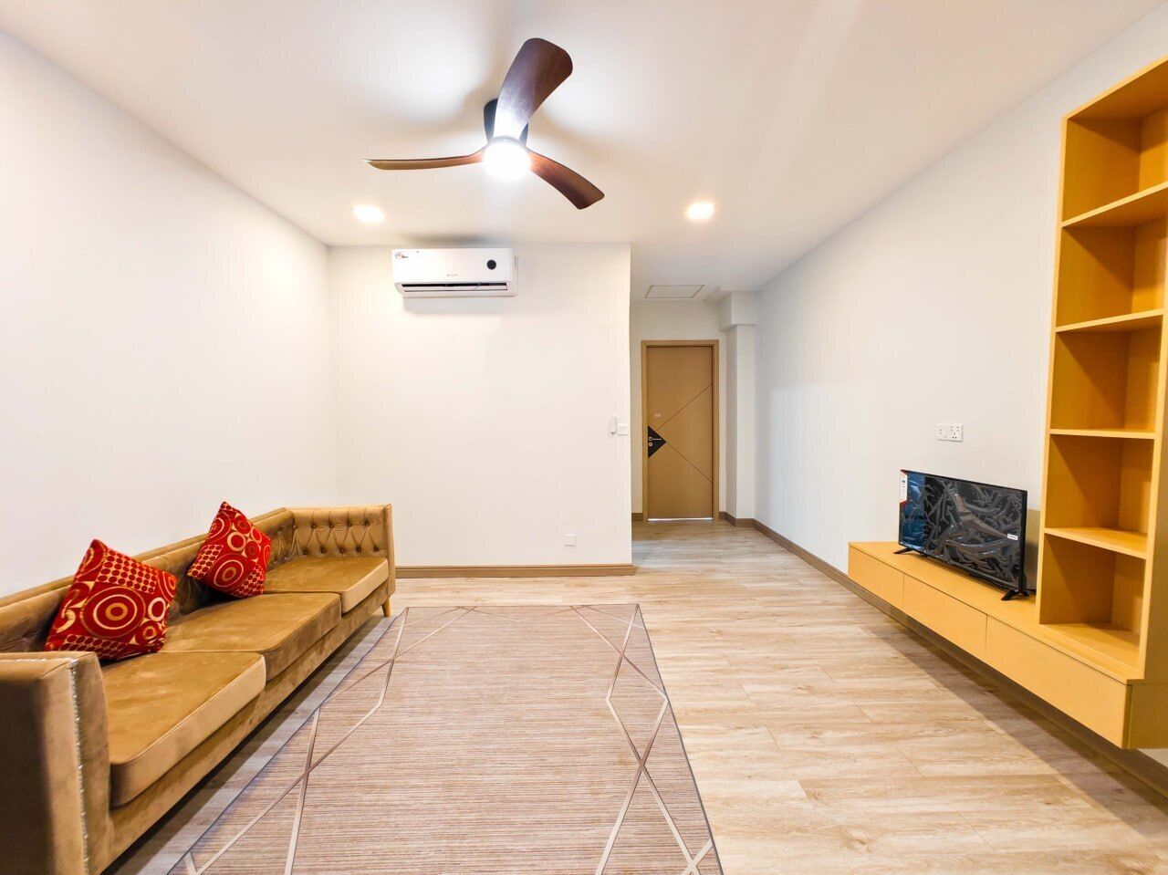 Uma sala de estar moderna com um sofá, uma televisão de tela plana e um ventilador de teto.