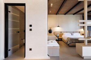 Quarto de hotel moderno com cama, mesa de cabeceira, luminária e vista para o horizonte urbano.
