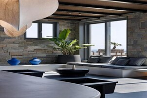 Um interior moderno com parede de pedra, grandes janelas, área de estar e espaço para refeições.