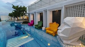 Uma piscina infinita com design arquitetônico moderno, incluindo fachada branca e painéis de parede estampados.