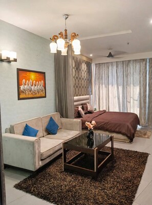 Quarto moderno com cama, sofá, mesa de centro e um quadro na parede.