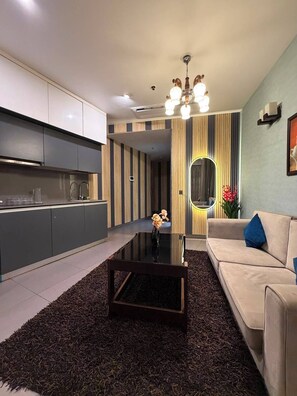Uma sala de estar moderna com sofá, mesa de centro e uma cozinha com armários e bancada.