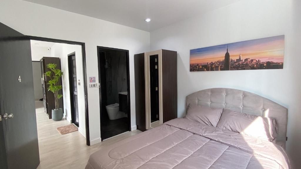 Quarto com cama, guarda-roupa, banheiro e pintura da paisagem urbana na parede.