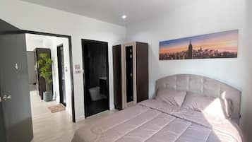 Quarto com cama, guarda-roupa, banheiro e pintura da paisagem urbana na parede.