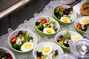 Uma variedade de tigelas com saladas e ovos cozidos sobre gelo.