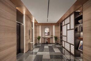 Um corredor moderno com chão quadriculado, paredes de madeira, um balcão de recepção e um biombo decorativo.