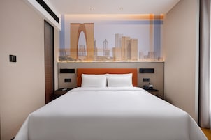 Quarto de hotel com uma cama grande, um mural com vista para a cidade na parede e uma cabeceira moderna.