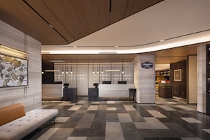 Uma área de recepção de hotel com balcão de check-in, espaço para sentar e um bar.