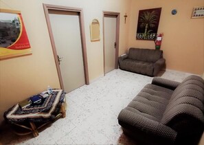 Um quarto com um sofá estampado, uma mesa pequena com um objeto decorativo e uma porta com um espelho.
