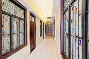 Um corredor com portas em ambos os lados, cada uma com grades metálicas decorativas.