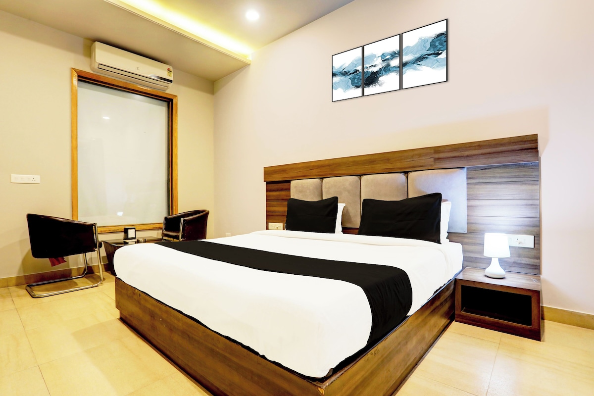 Quarto moderno com uma cama grande, mesa de cabeceira, cadeira e ar condicionado fixado na parede.