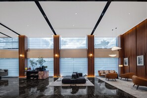 Um lobby moderno com balcão de recepção, área de estar e grandes janelas.