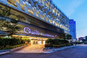 Um hotel moderno com um letreiro iluminado que diz 'Owl Residences'.