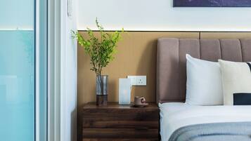 Quarto de hotel com uma cama, uma mesa de cabeceira com uma planta, uma xícara e uma tomada.