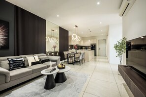 Uma sala de estar moderna com sofá, mesa de centro e um espaço de jantar com cadeiras e uma mesa.