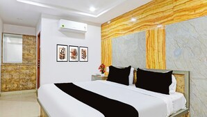 Quarto de hotel com cama, mesa de cabeceira, espelho e ar condicionado fixado na parede.