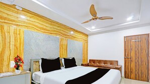 Quarto de hotel com cama, cabeceira de madeira, ventoinha de teto e porta de madeira.