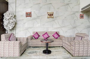 Uma área de estar com um sofá estampado, uma mesa redonda e almofadas decorativas.