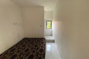 Um corredor estreito com uma cama estampada no final, que leva a uma pequena janela com vista para o verde.